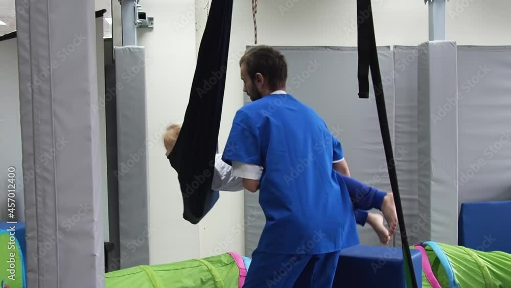 Child girl with physiotherapist swinging on swing during sensory ...
