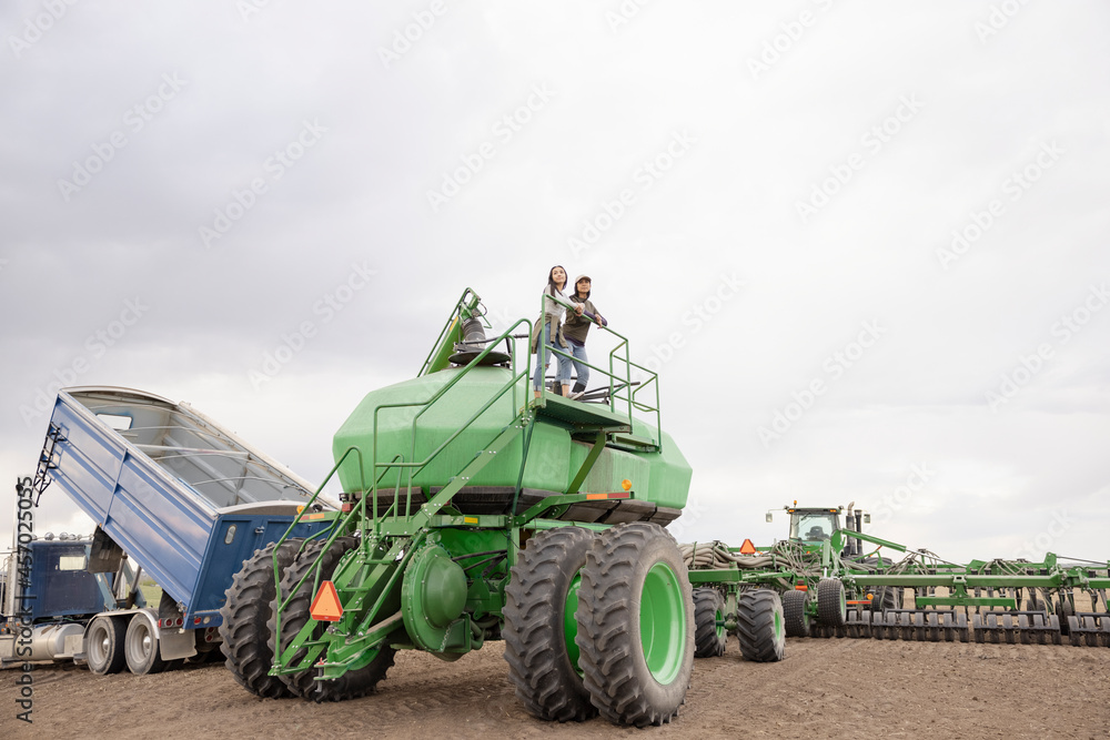 Mother and daughter farmers on farming equipment platform on farm Stock ...