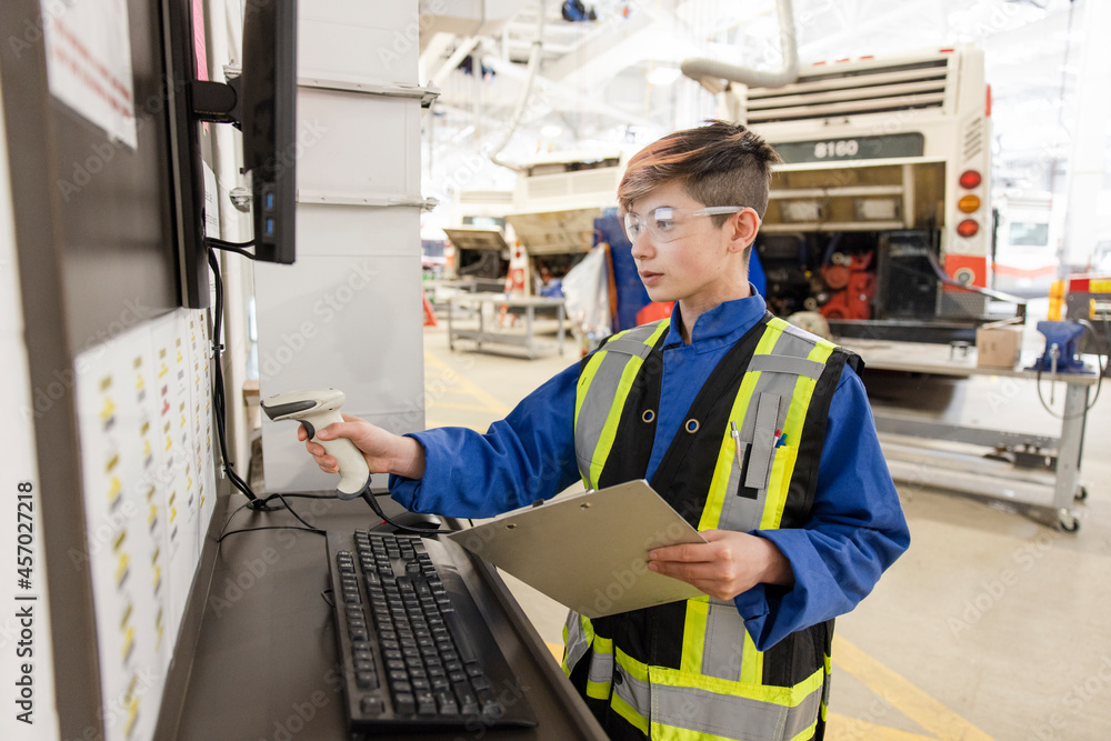 Nonbinary worker scanning paperwork in maintenance facility Stock Photo ...