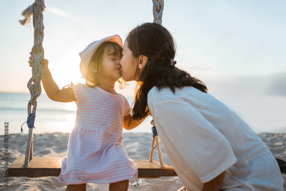 daughter kissing her mother while swinging at the beach Stock Photo ...