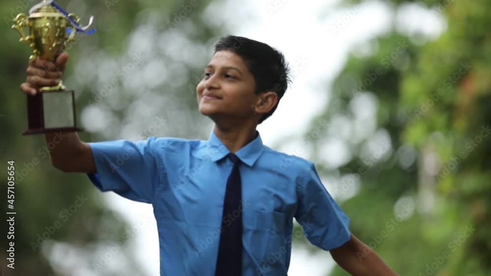 Clever schoolboy raising his trophy as a winner in school competition ...