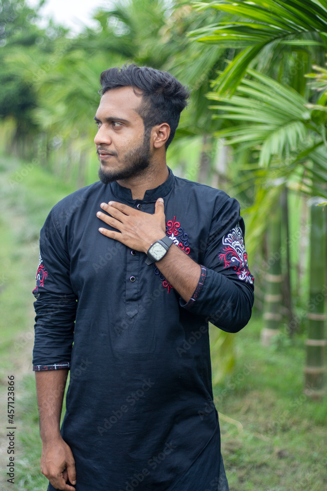 A Young Man With A Small Beard Is Standing To Wear A Dark Blue Design Panjabi And His Behind