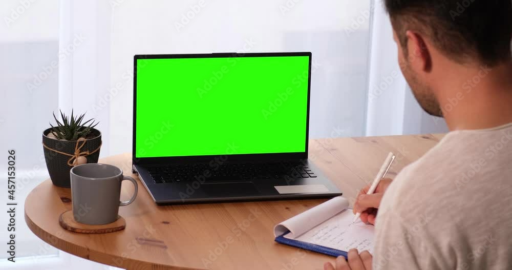 Man taking notes with personal computer mock-up chroma key display ...
