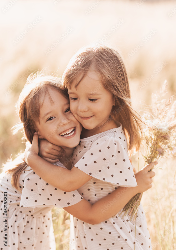 Two little happy identical twin girls playing together in nature in ...