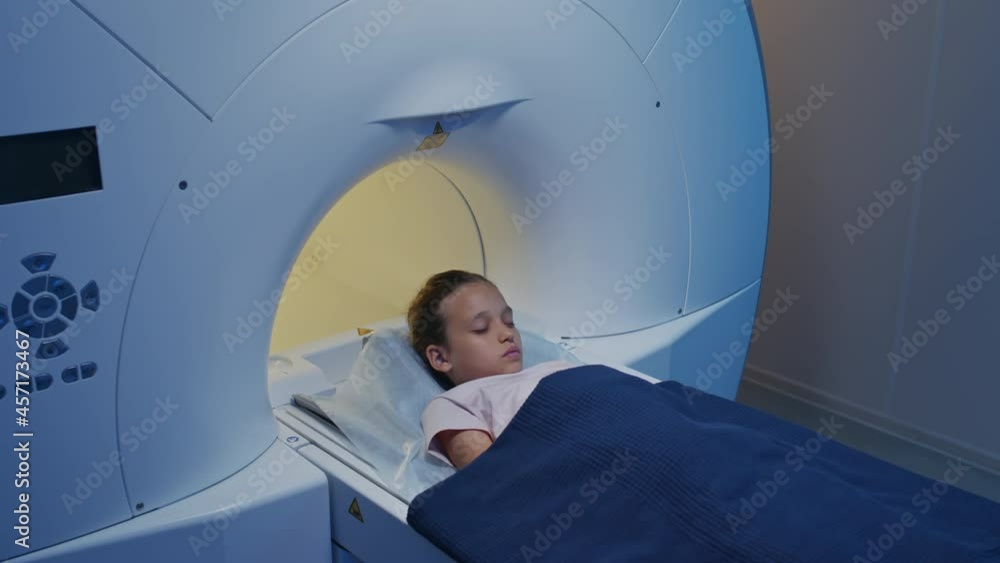 Slowmo shot of little girl on scanner table getting inside MRI machine ...