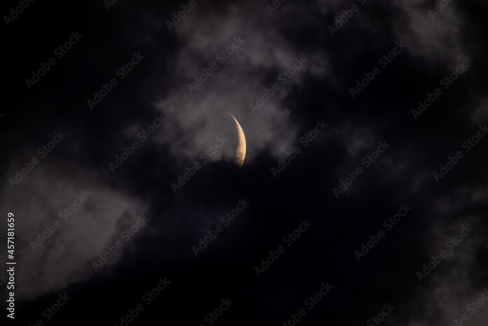 crescent moon behind dark clouds Stock Photo | Adobe Stock