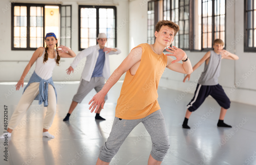 Teenage boy practicing hip hop moves with friends at group dance class ...