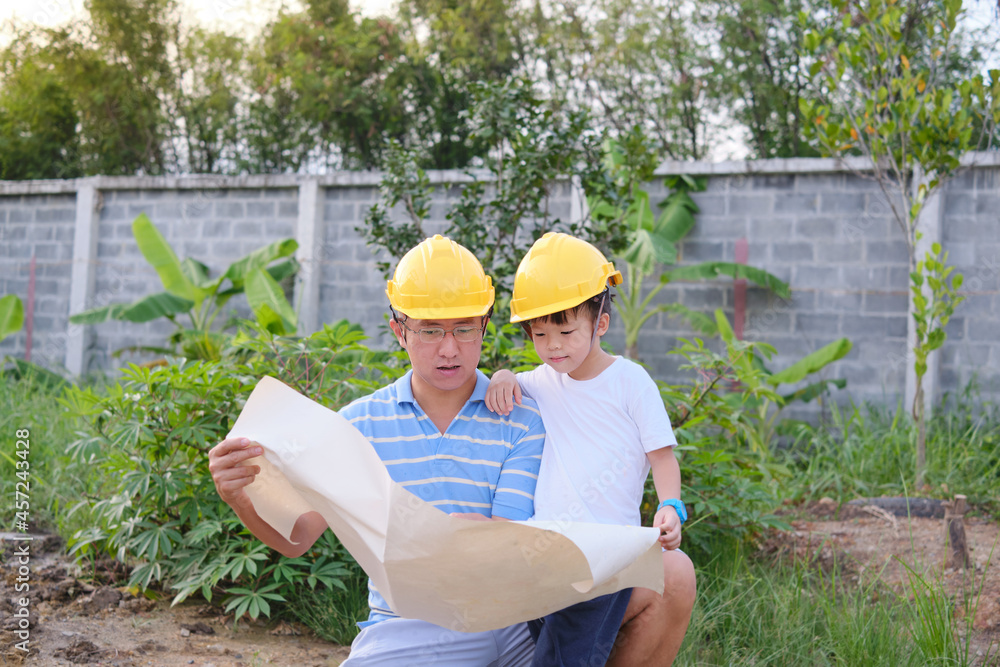 Smiling happy Asian Dad and son wearing yellow construction helmet or ...