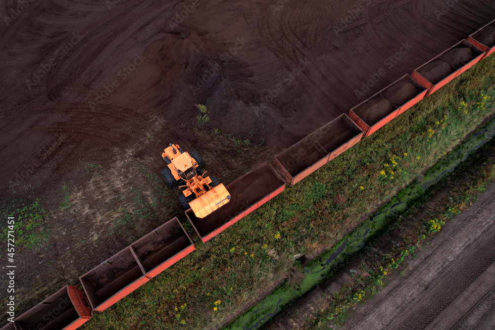 Wheel loader loads peat in freight cars. Aerial view of diesel ...
