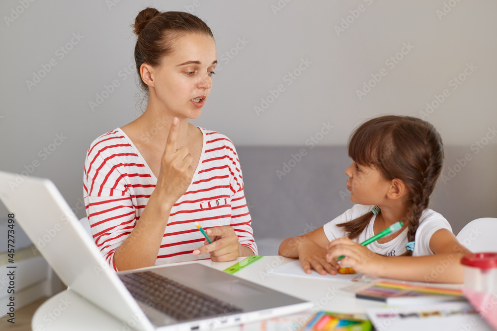 Caucasian girl studying with mother or teacher at study table with ...