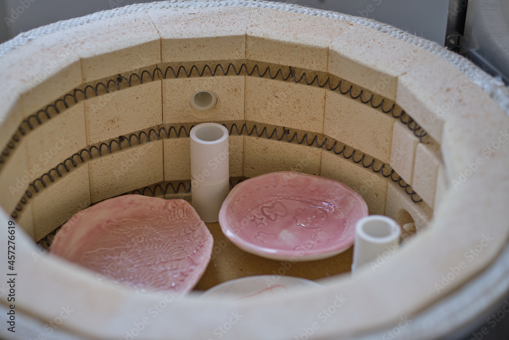 female potter put it into a kiln for firing. Kiln in Potter's workshop ...