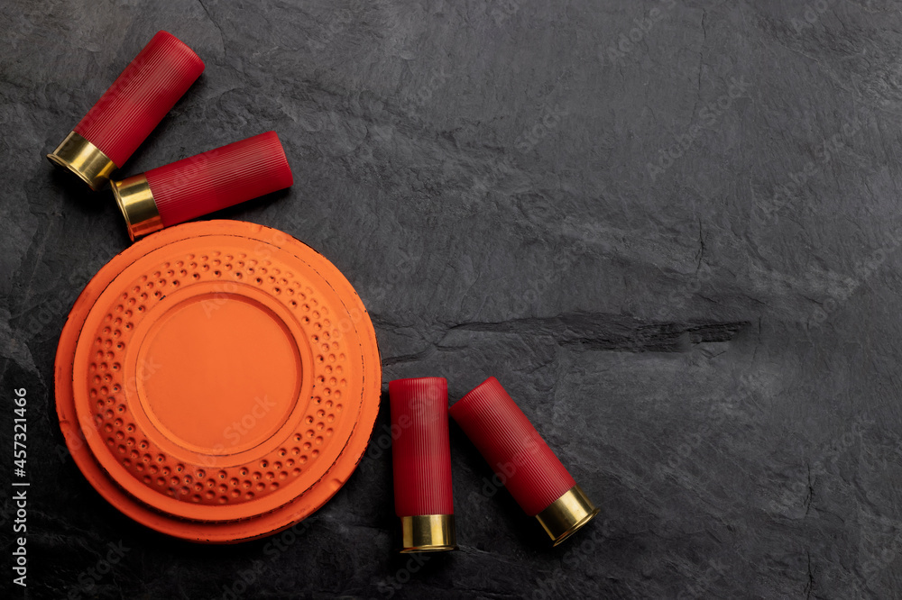 Clay shooting target with shotgun shell on black slate background ...