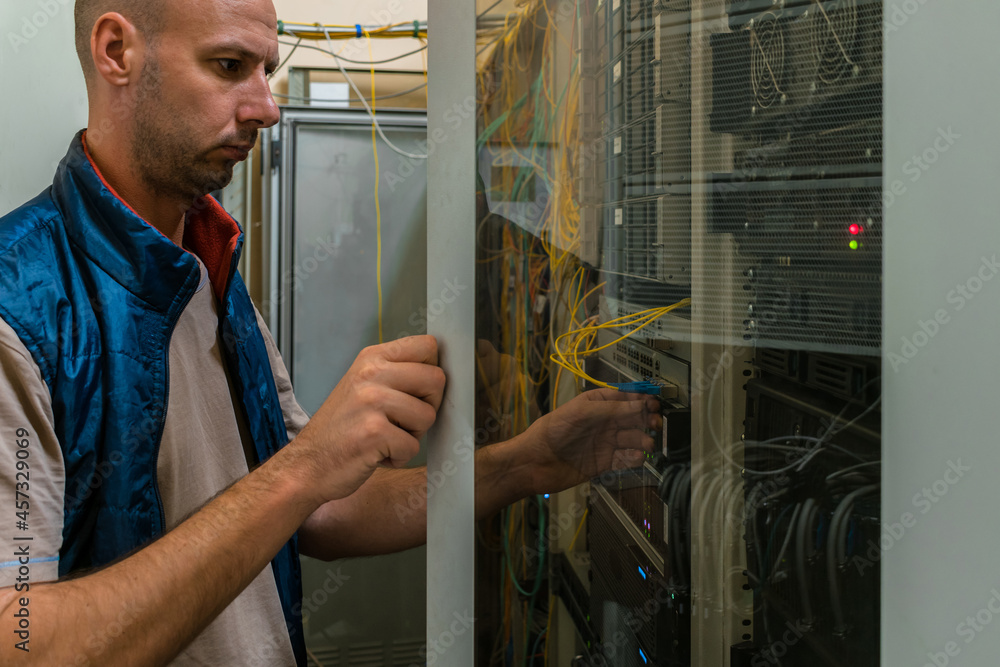 An engineer connects the fiber optic cable to the switch's network ...