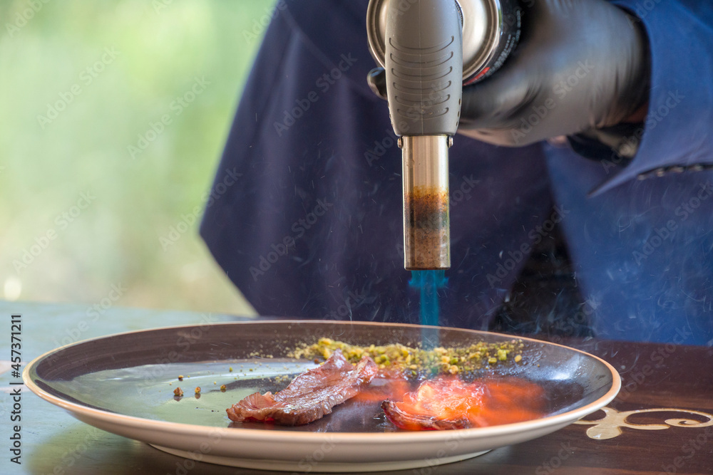 Chef cooking beef with a blowtorch in a Michelin-starred restaurant ...