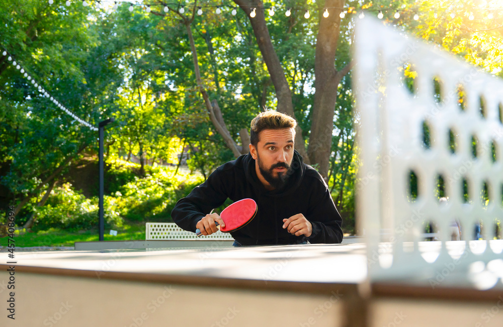 Street table tennis on the open air ground. Game focused man plays ping ...