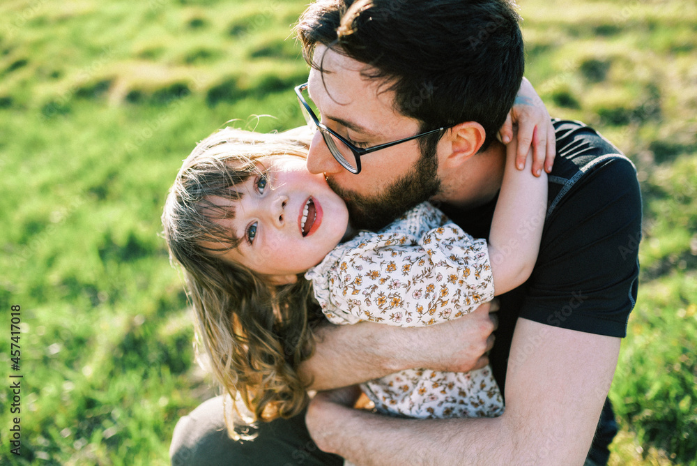 Happy little toddler girl hugging her father with glasses and smiling ...