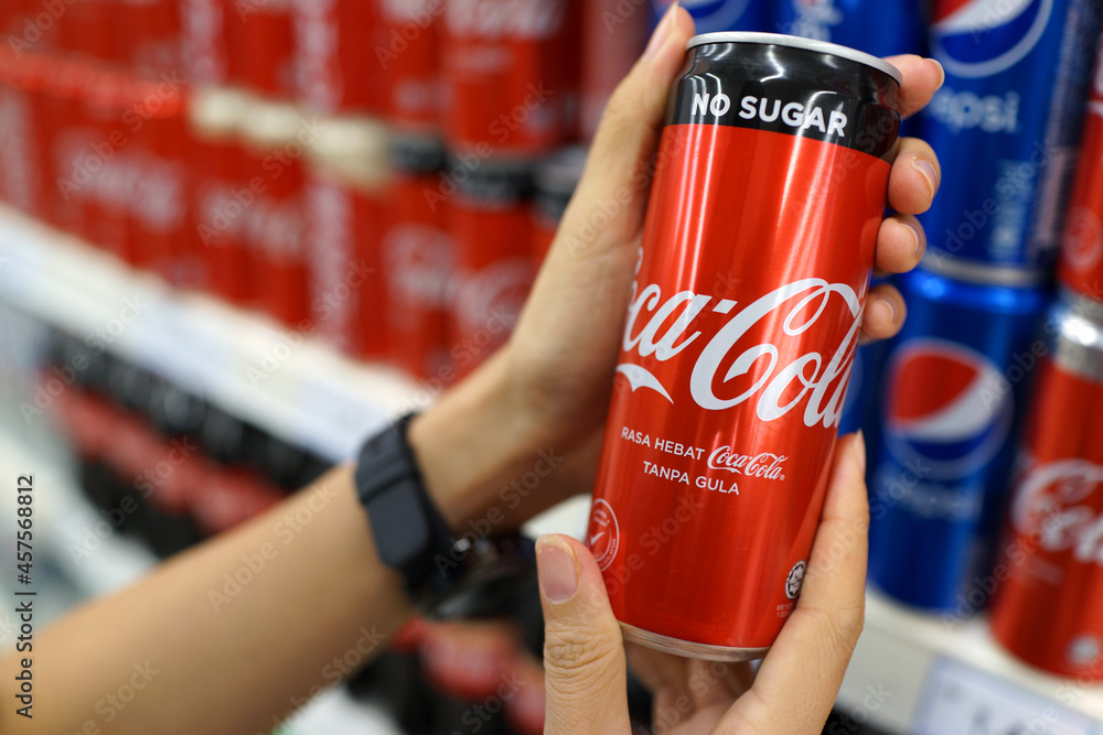 Hands Holding a can of Coca-Cola drink in a grocery store. Coca-Cola ...