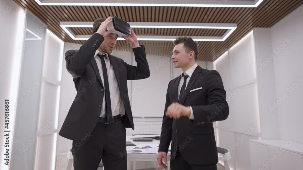 Satisfied client taking off VR headset shaking hands talking to ...