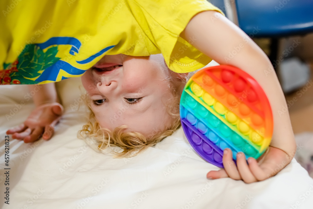 girl covered her face with a multi-colored round pop it. Blond girl ...