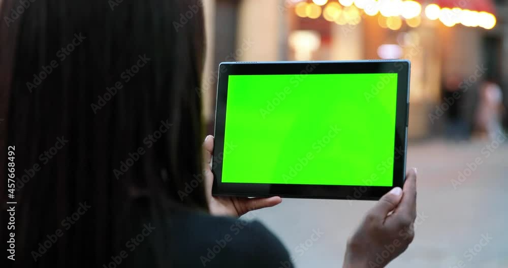 Female hands holding tablet with green screen. Girl using mobile phone while walking in the ...