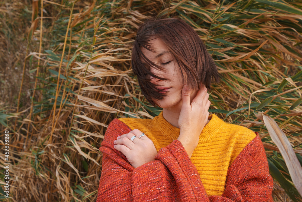 Attractive young woman standing on a windy cold beach wrapped in warm ...