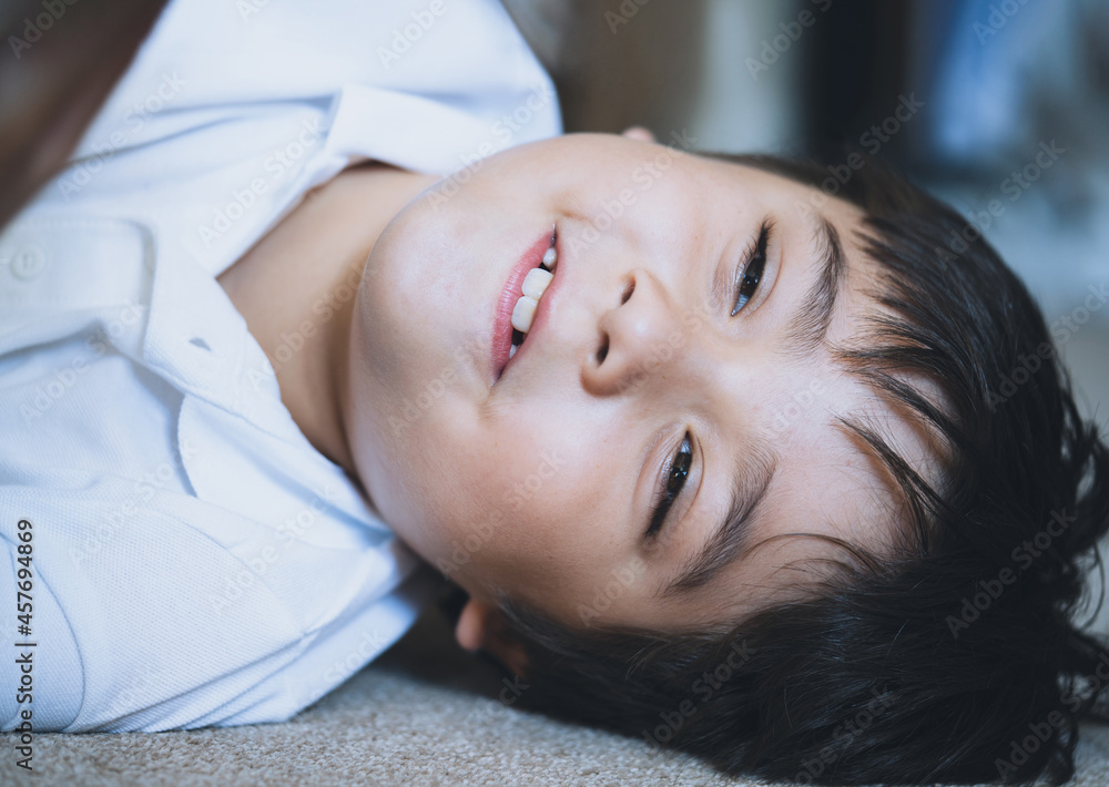 Close up face of cute little child boy lying on carpet, Candid shot ...