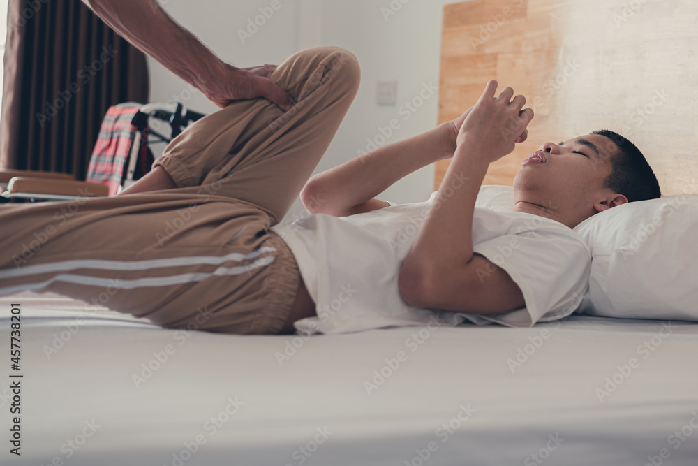 Disabled teenager boy doing physical therapy by parent on bed,Lifestyle ...