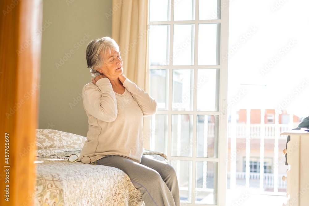 Senior woman suffering from neckache after sleep, rubbing stiff muscles ...