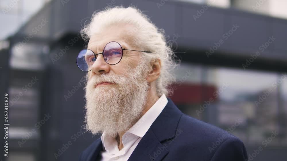 Serious old man with long white hair and beard looking into distance ...