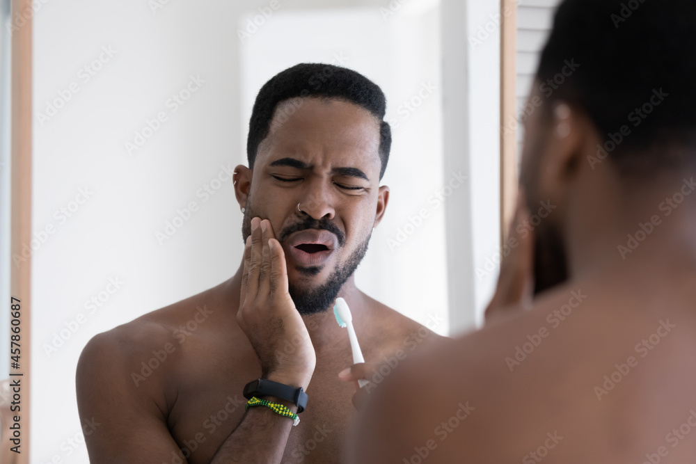 Handsome 30s African guy with frown face expression reflected in mirror ...