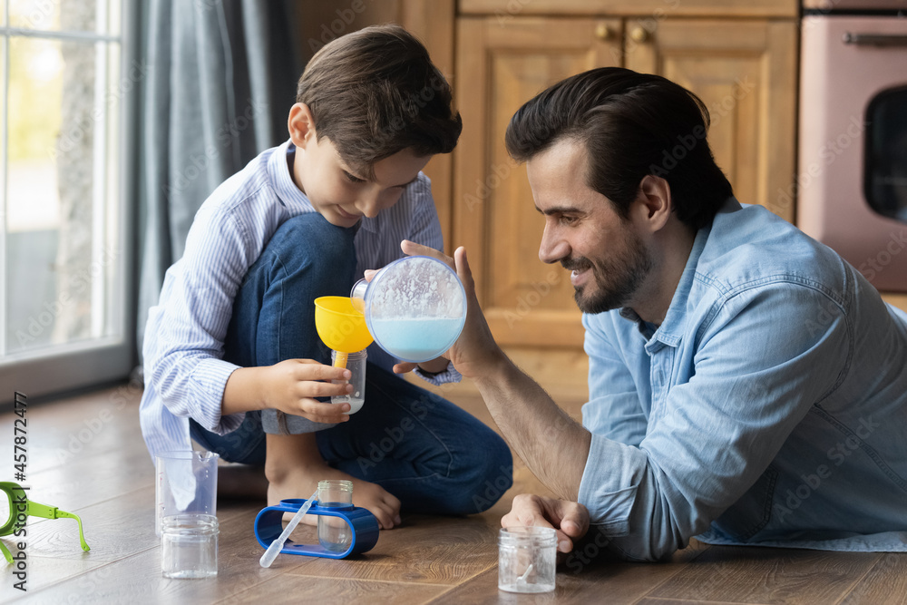 Smiling father and little son having fun with toy chemistry laboratory ...