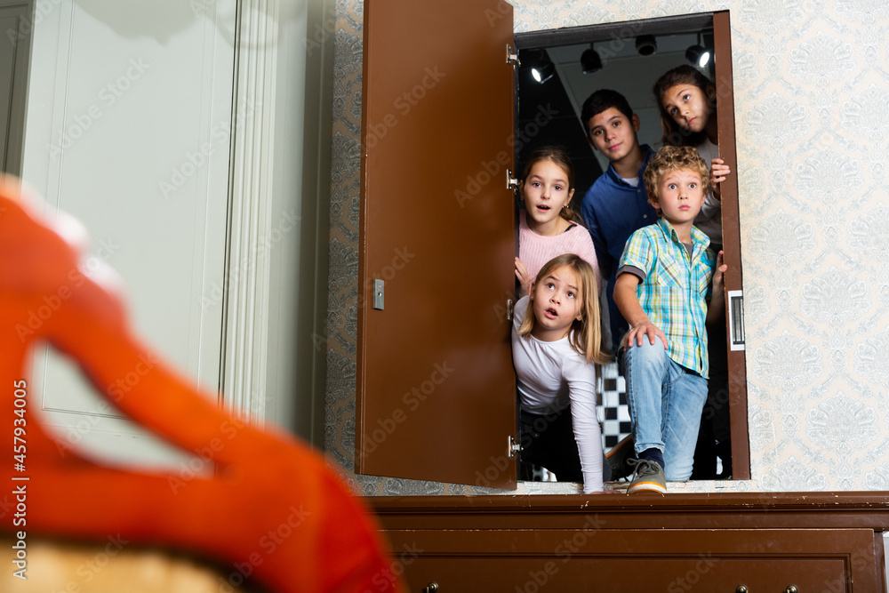 Surprised tween children peeking into quest room through open door in ...