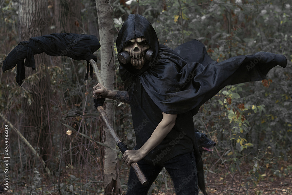 a man in a scary mask and black clothes with a scythe in a gloomy ...