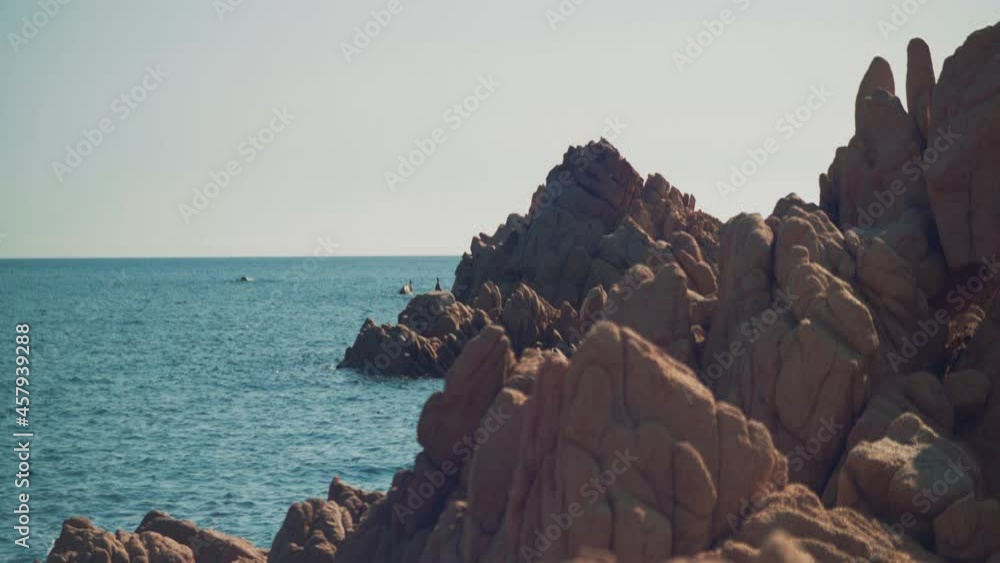 Calm Sardinia rocky beach seaside with blue water, red round rocks and ...