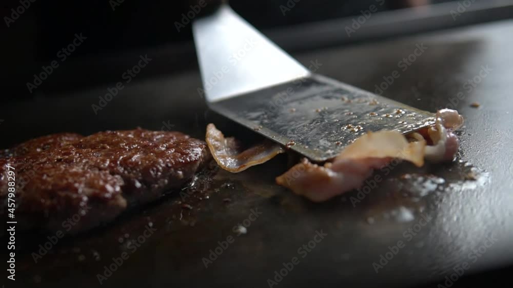 Cooking raw beef patty and pork bacon for burger. Chef frying roasted ...