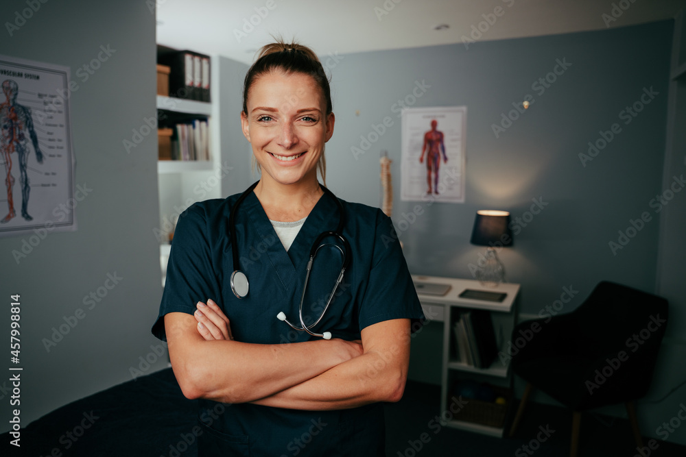 Caucasian female nurse standing with arms crossed in medical clinic ...