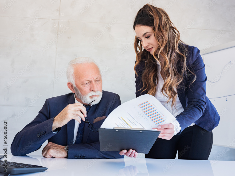 Young assistant showing graphs, charts to old businessman, analyzing ...