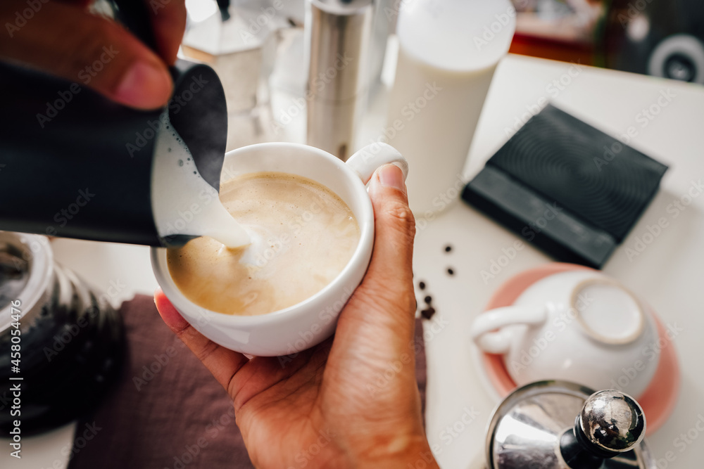 barista's hand making hot coffee mugs, latte art and pitcher made of ...