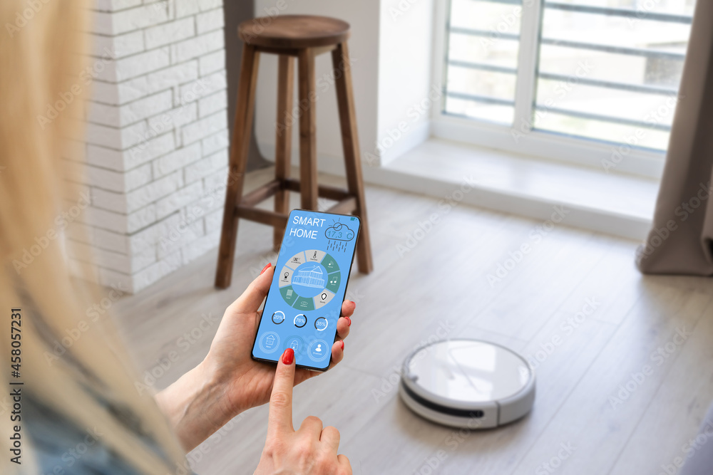 female hand holding phone with smart home on the screen in the room ...