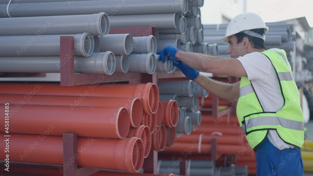 Warehouse employee choosing plastic pipe carrying manufactured product ...