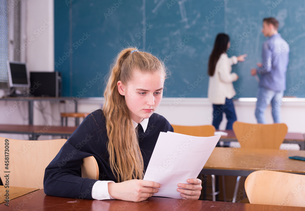 Portrait of frustrated teen girl student sitting in classroom with ...