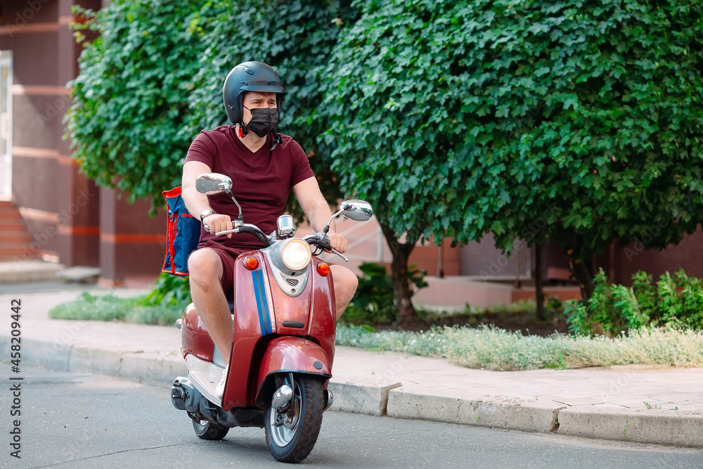 Delivery boy wearing red uniform on scooter with isothermal food case ...