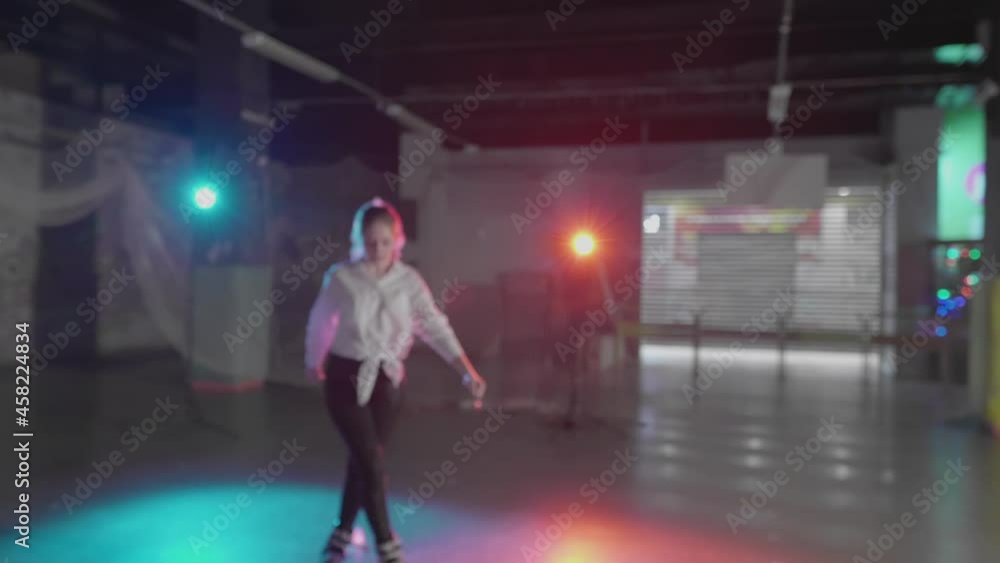 Group of teenage girls roller-skating in dark studio. Millennials ...