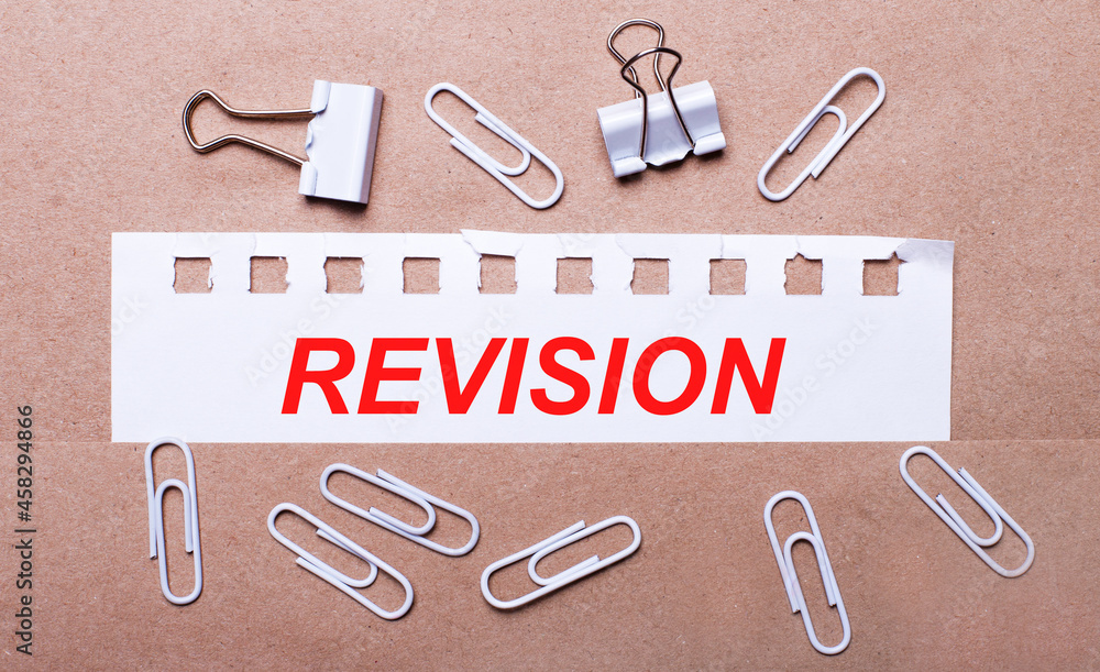 On a brown background, white paper clips and a torn strip of white ...