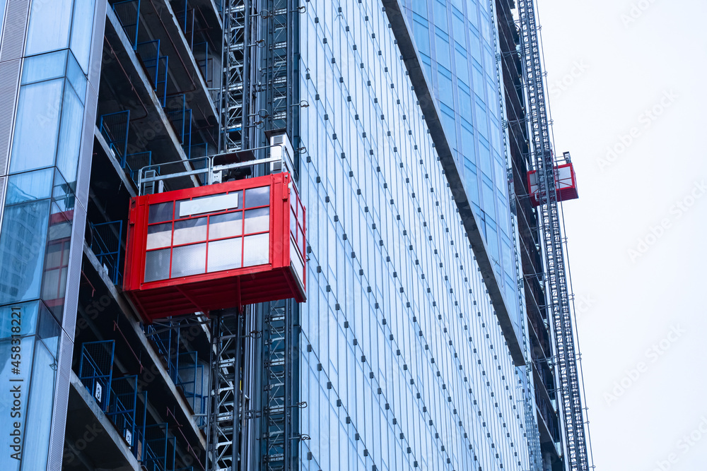 Freight construction elevator ascends to top of a skyscraper. Temporary ...