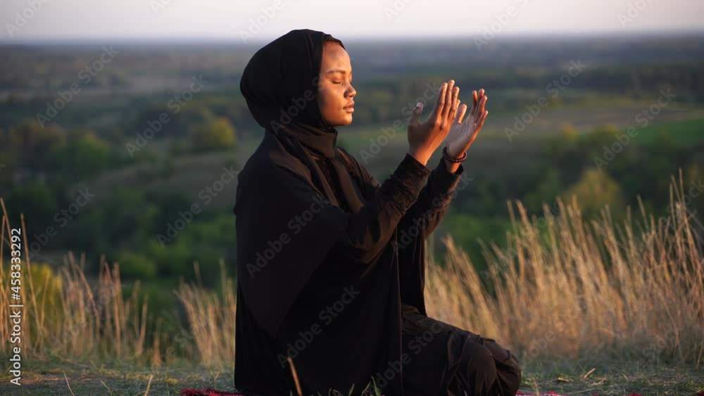 Vidéo Stock Black muslim woman in robe sitting on the carpet. Solat ...