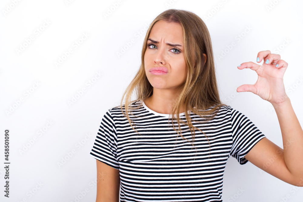 Displeased beautiful blonde girl wearing striped t-shirt on white ...
