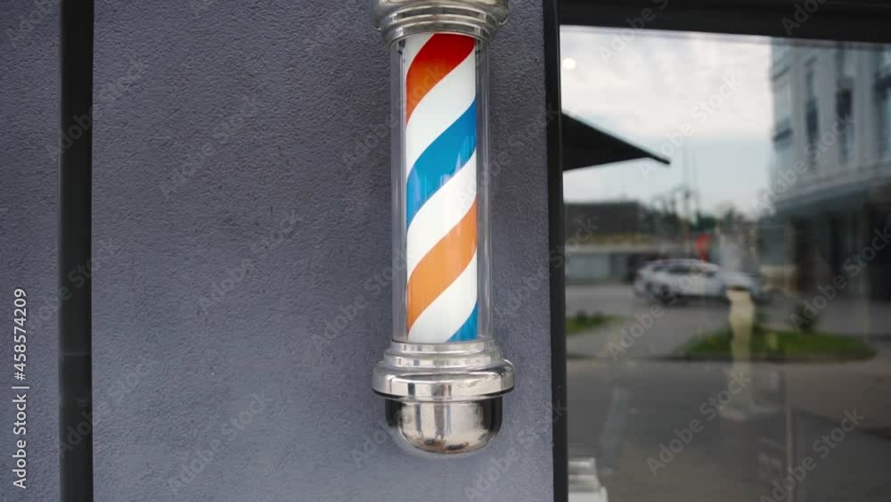 Barber pole on wall in hairdresser shop. Barber pole spinning at ...