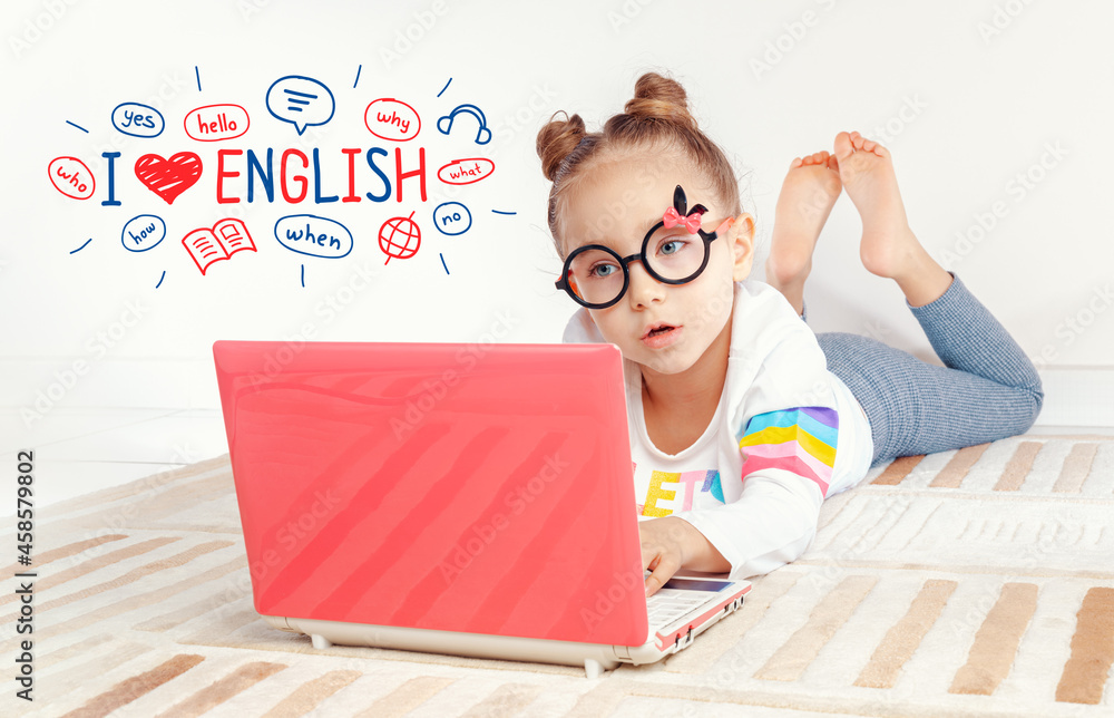 Beautiful cute little girl laying on carpet and using laptop computer ...