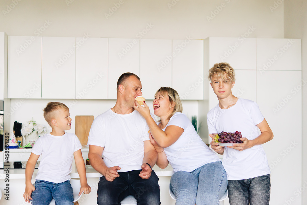 Cheerful family at home. Mom, dad and two sons. They eat pastries ...